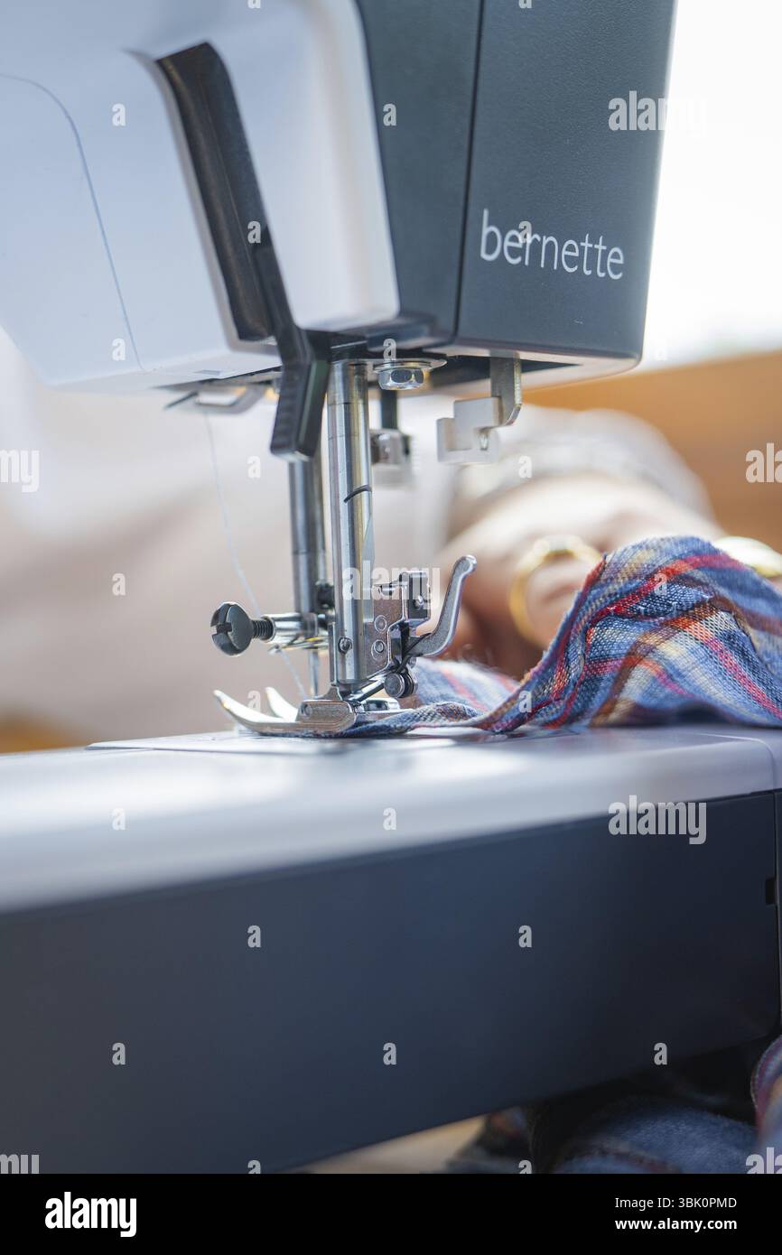 Close-up of the needle of a sewing machine sewing a chequered fabric in ...