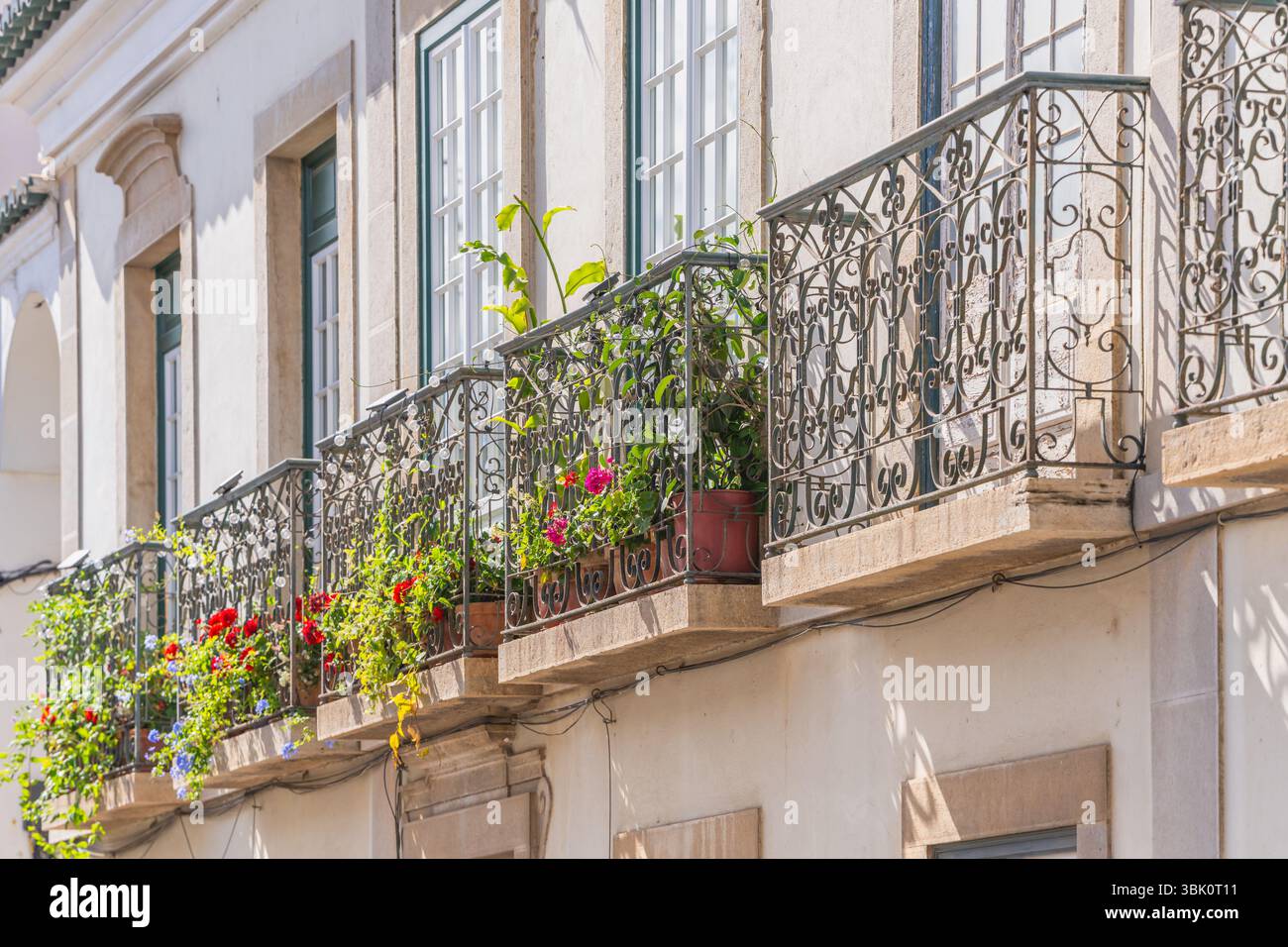 Decorative wrought iron balconies overflow with colorful flowers and ...