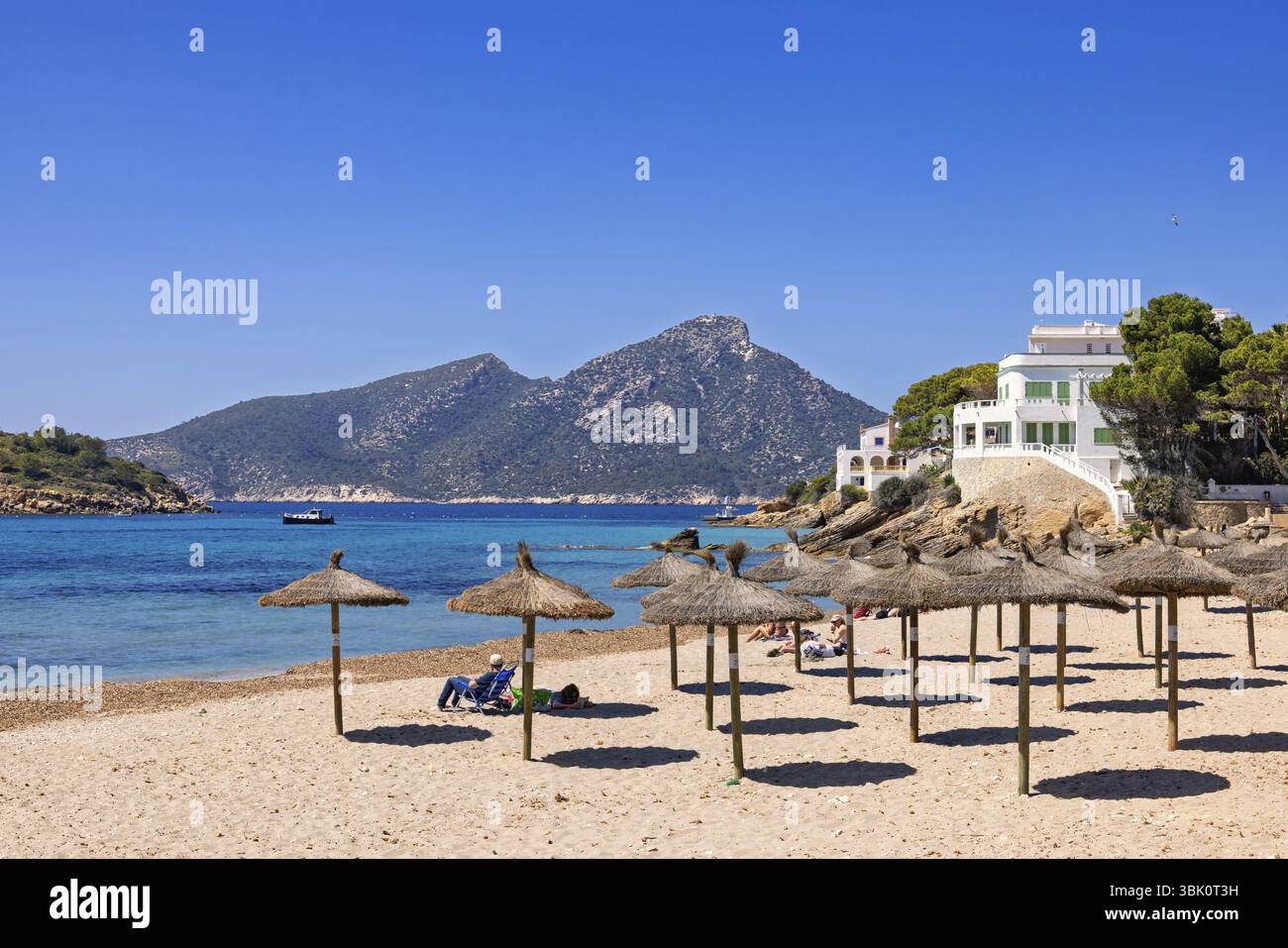 People sunbathing on a sandy beach with parasols by the Mediterranean ...
