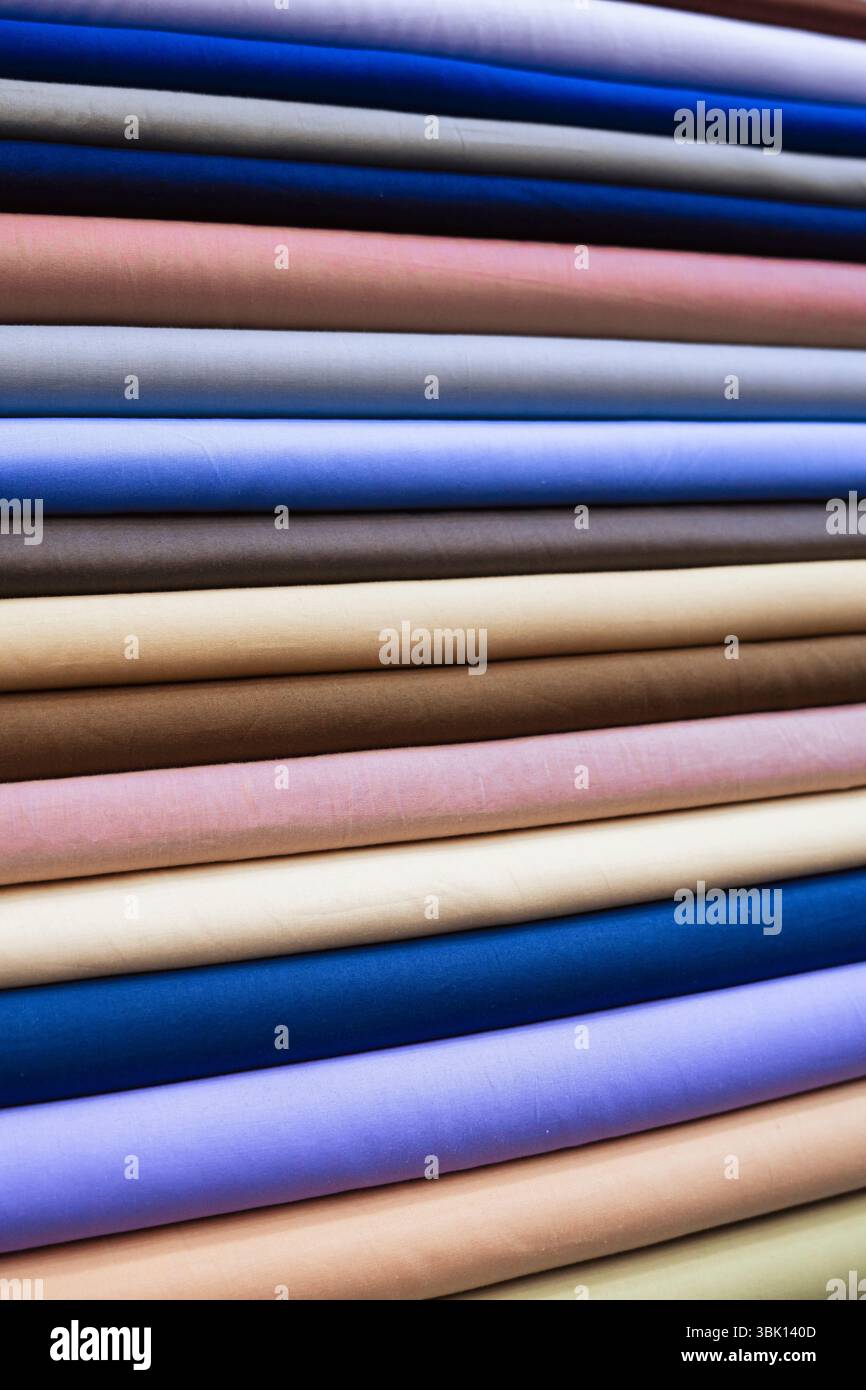 A close-up photograph showcases numerous rolls of fabric neatly stacked ...