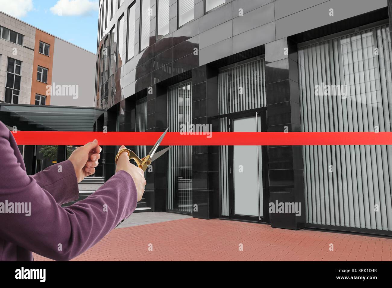 Woman cutting red ribbon at opening ceremony of office building ...