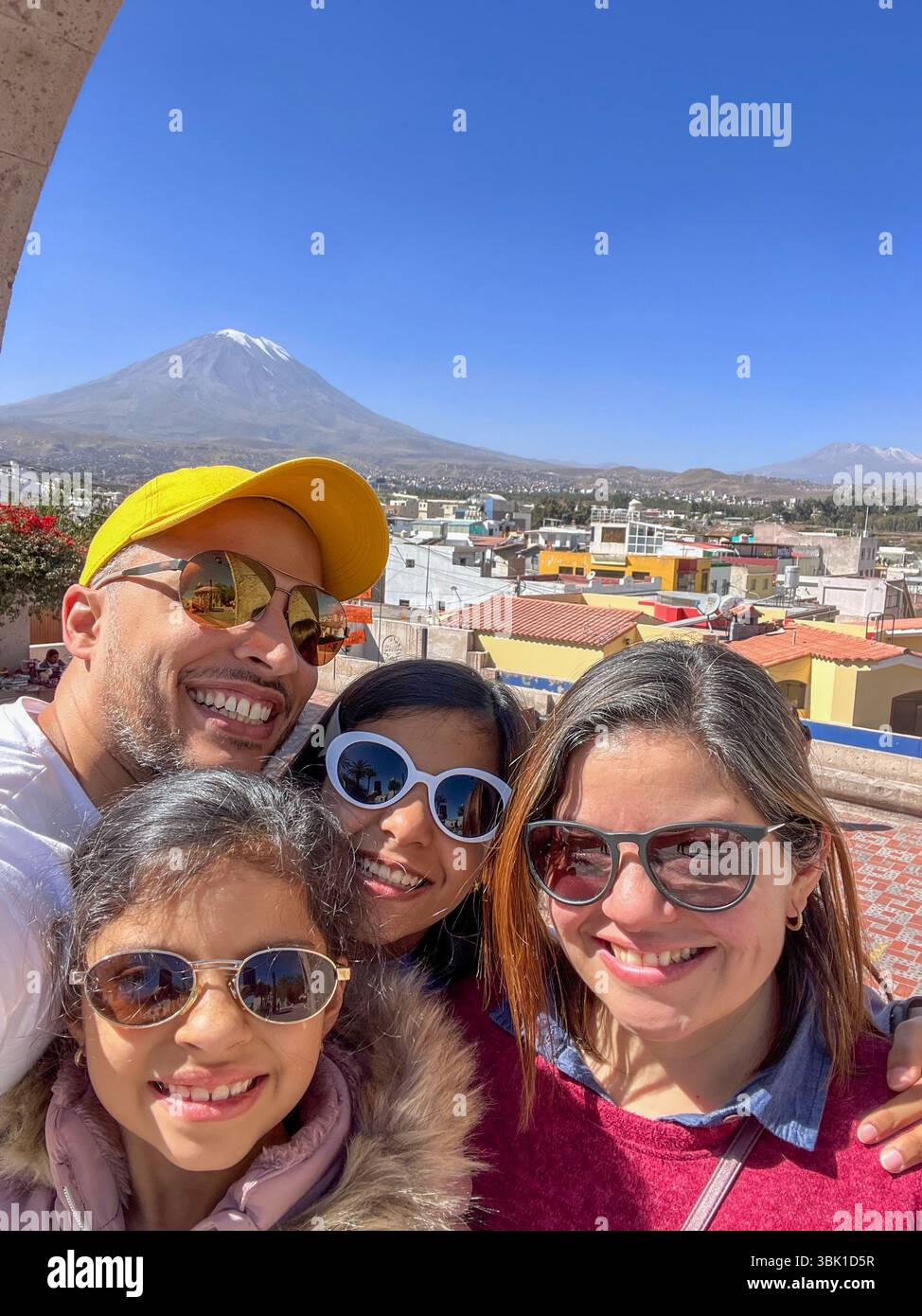 A family are posing for a picture with a Arequipa city in the ...