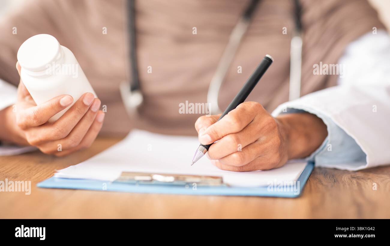 Female doctor holding medicine, writing prescription in medical chart ...