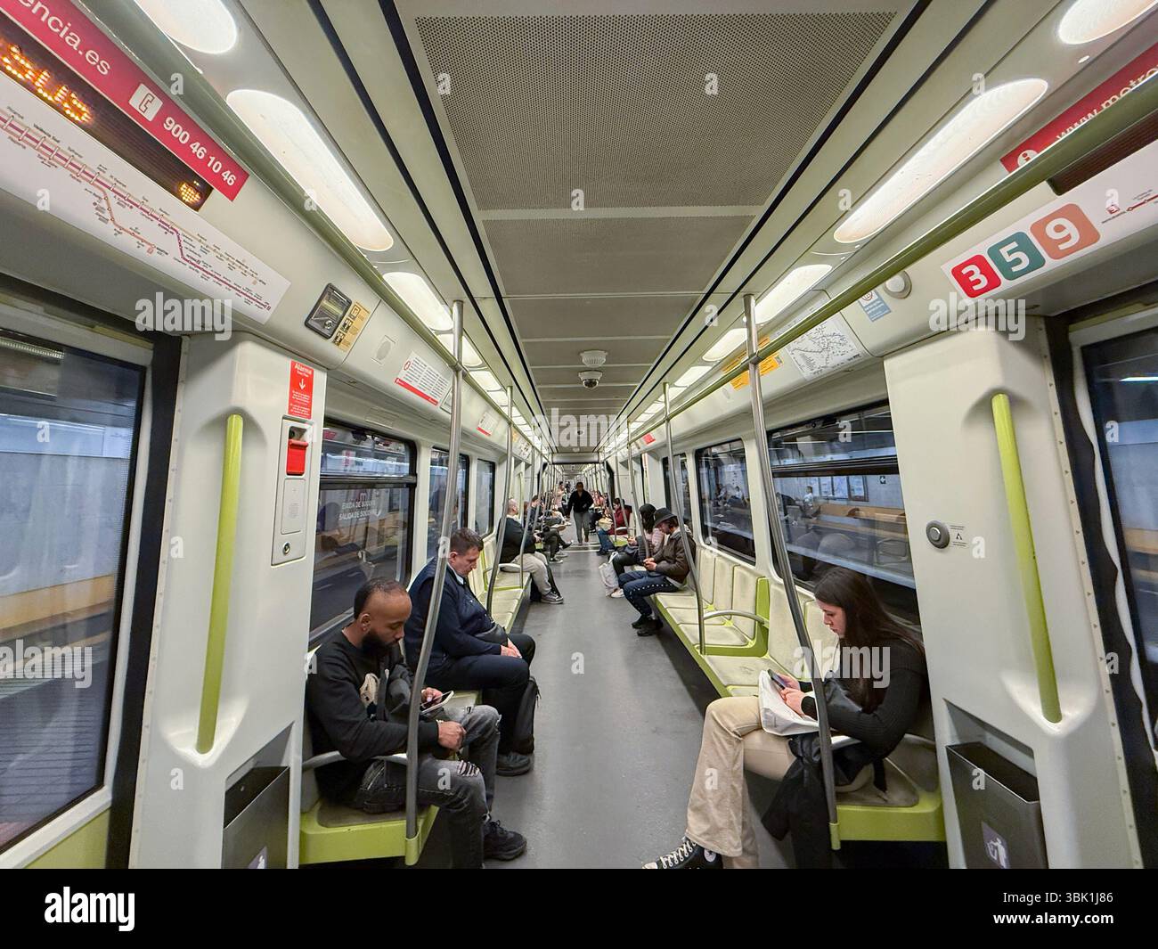 VALENCIA, SPAIN - APRIL 15, 2025: Commuters sit on light green benches ...
