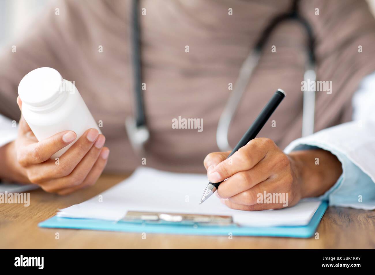 Female doctor holding medicine, writing prescription in medical chart ...