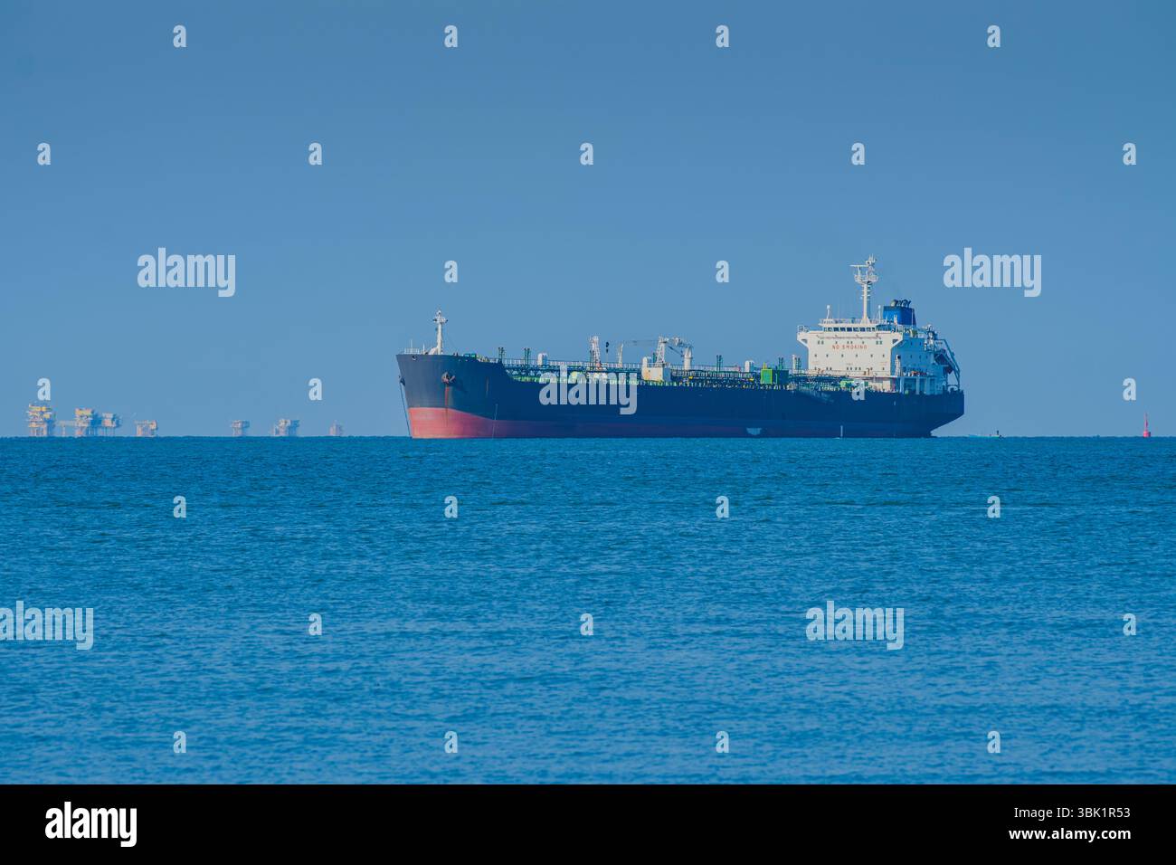 A large, modern tanker ship with black hull and red bottom, sails ...