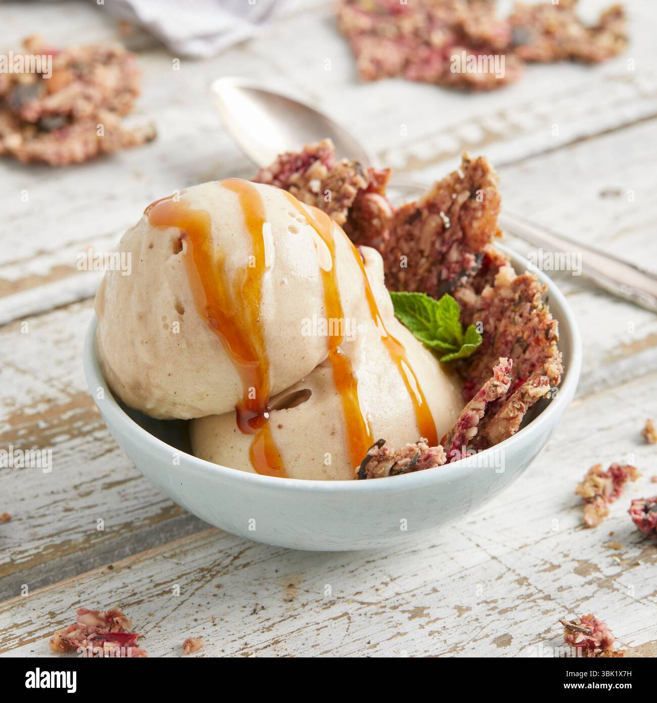 Scoops of banana nice cream topped with caramel sauce and biscuit ...