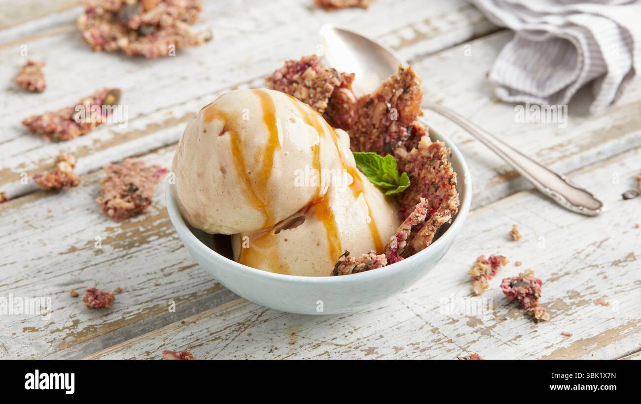 Scoops of banana nice cream topped with caramel sauce and biscuit ...