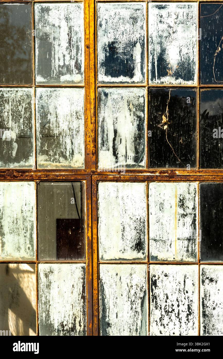 Cracked and peeling window panes reflect light and nearby objects ...