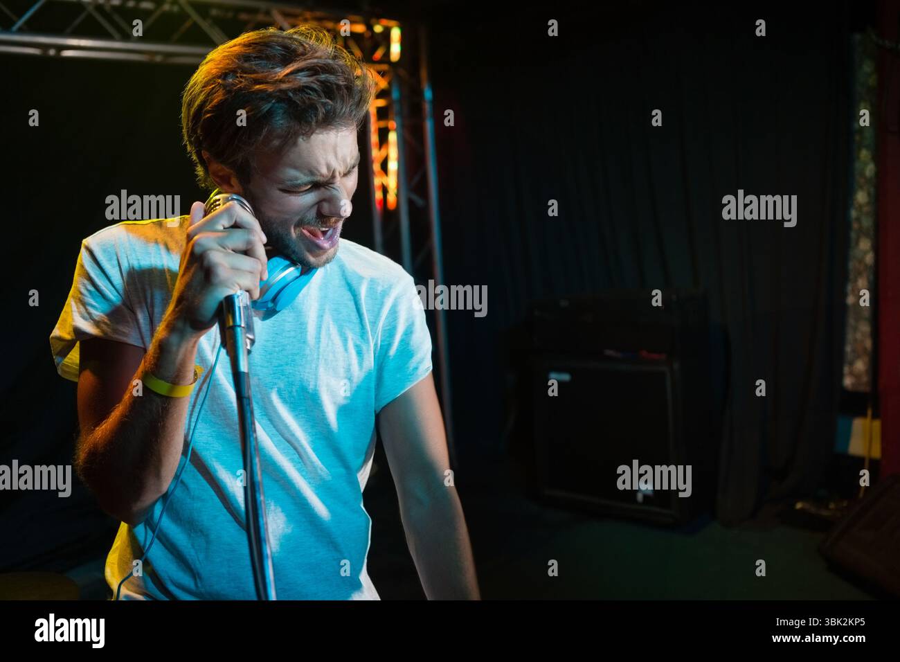 Male singer holding mic stand and singing passionately on stage with ...