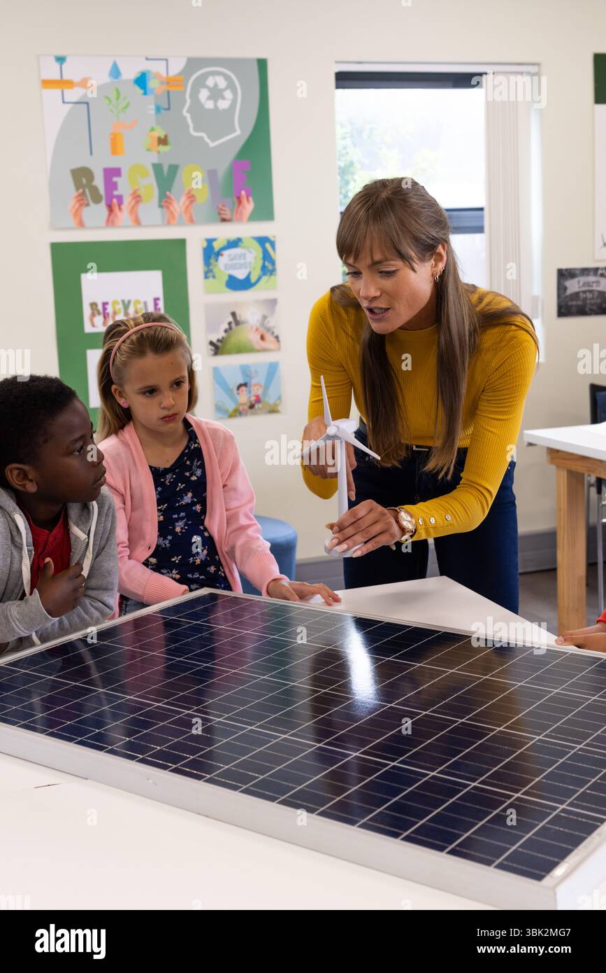 Female teacher explaining wind turbine model to attentive diverse ...