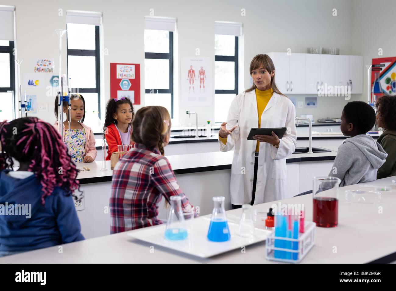 Female teacher explaining science experiment to attentive diverse ...