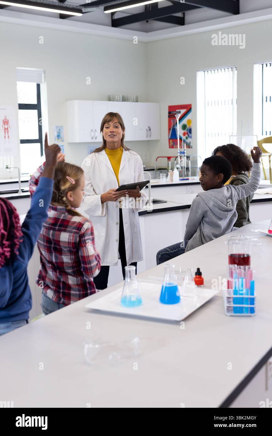 Leading science experiment, female teacher with diverse students in ...