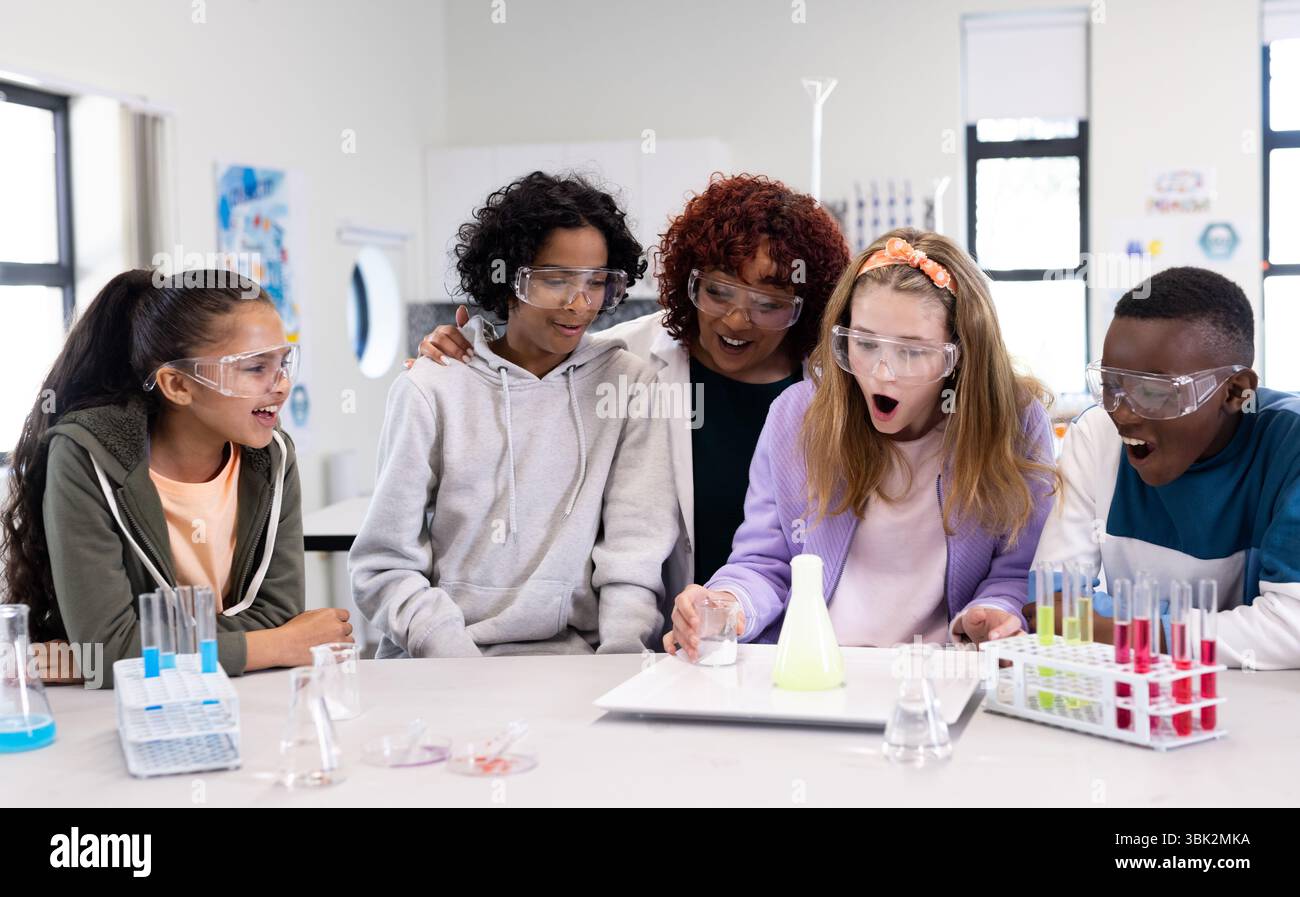 Conducting experiment in science class, diverse students observing chemical reaction, at school ...