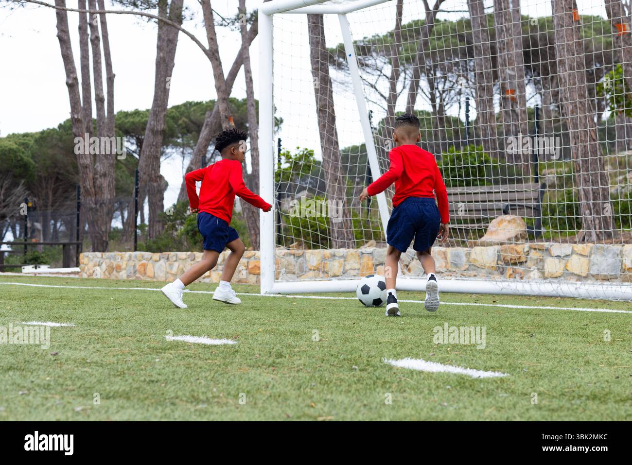 Diverse boys playing soccer outdoors, running towards goal with ...