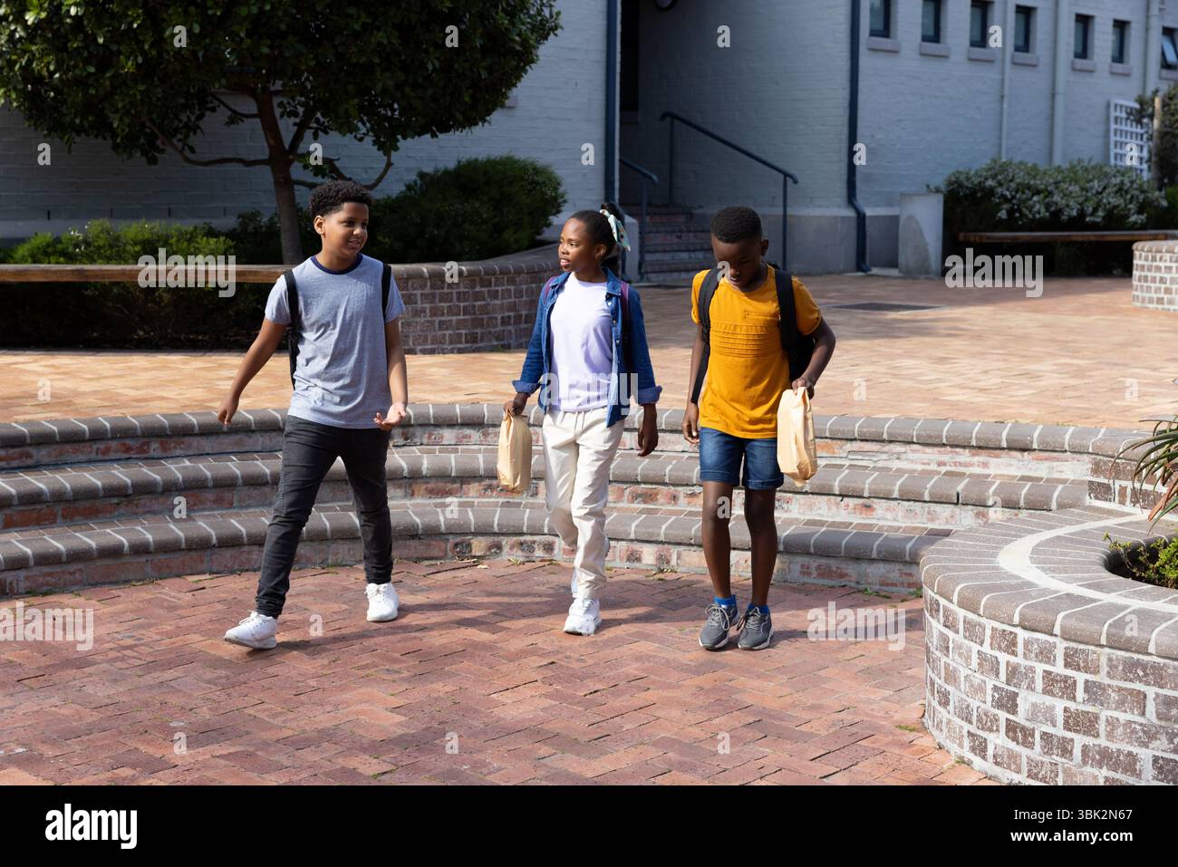 diverse students walking outside school, carrying lunch bags and ...