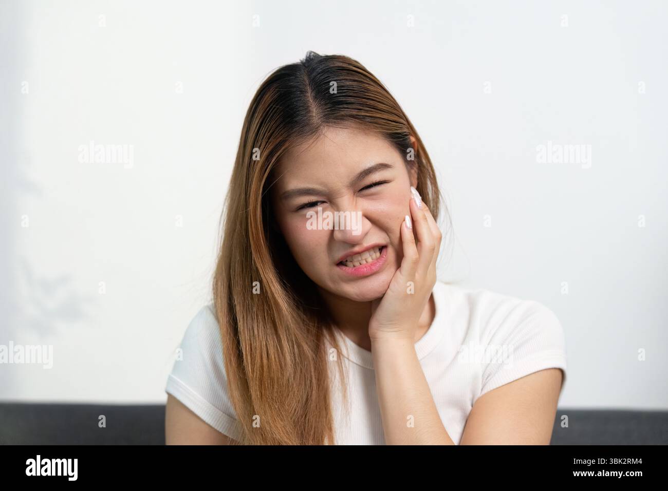 Toothache and Facial Discomfort. Young woman grimacing in pain at home ...