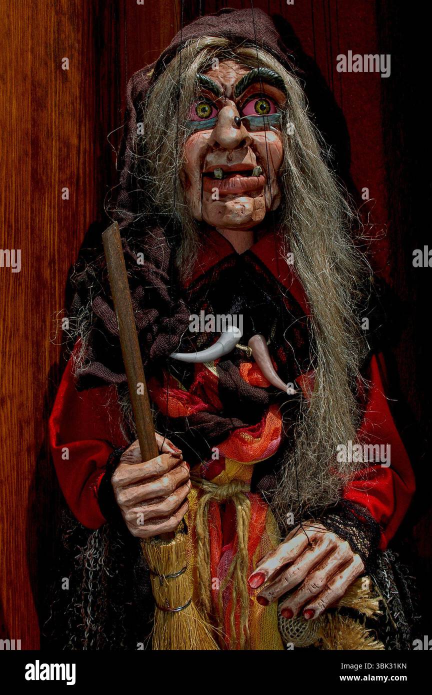 Fearsome pink-eyed witch puppet holding a broomstick and with ...