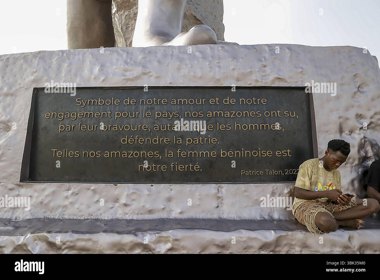Young man sitting at the foot of the Amazon monument in Cotonou, Benin ...