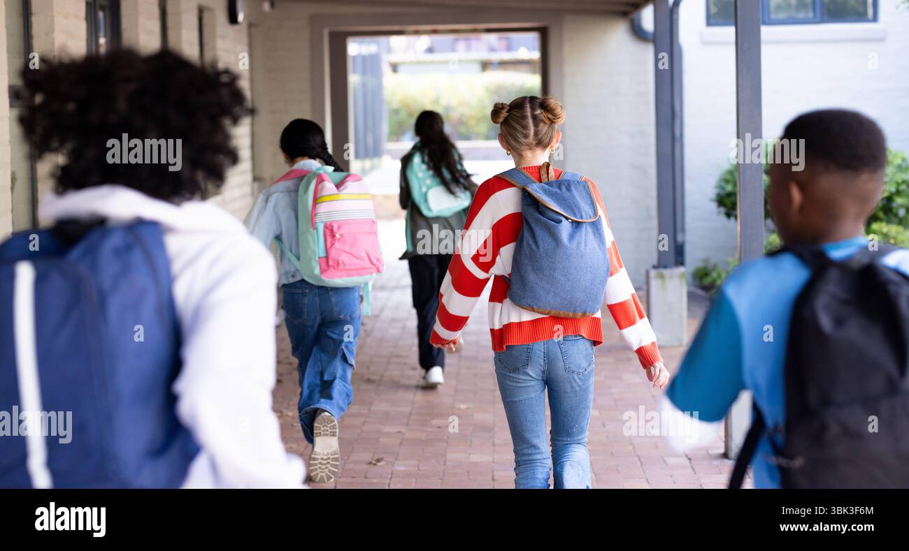 Diverse students walking together with backpacks in school hallway ...