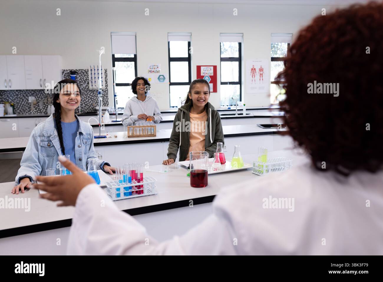 Diverse students in science class engaging with female teacher ...