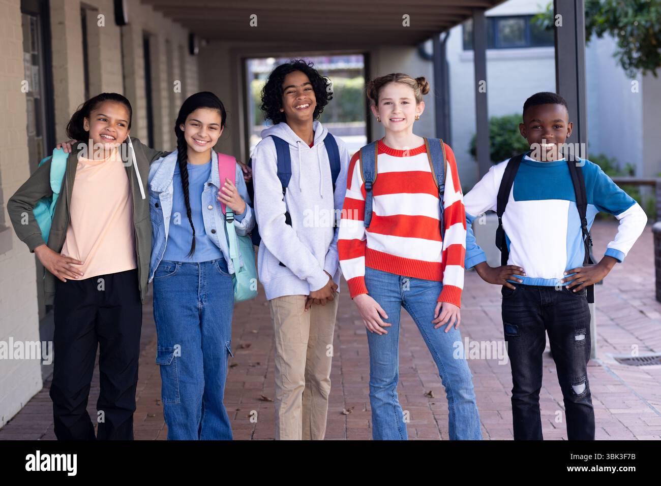 Diverse group of students smiling with backpacks outside school ...
