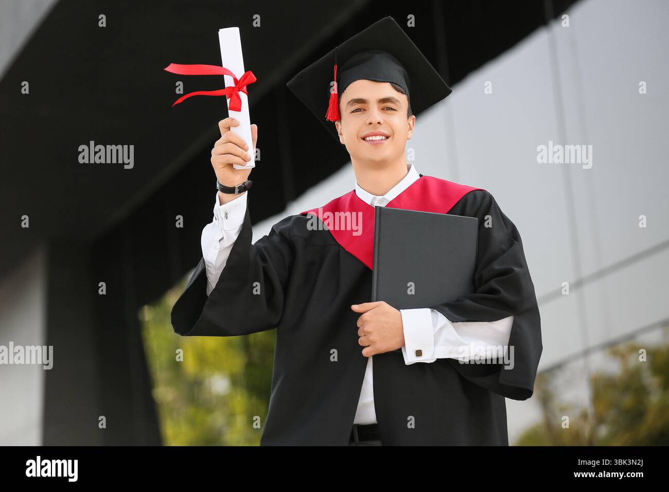 Male graduating student with diploma and book near university Stock ...