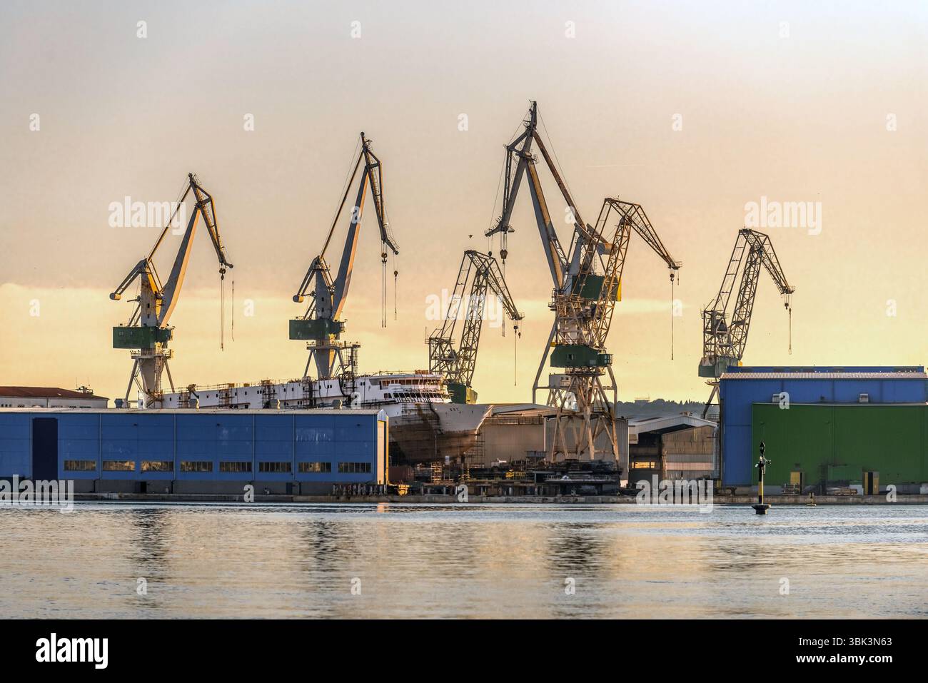 Industrial cargo cranes in the dock at sunset Stock Photo - Alamy