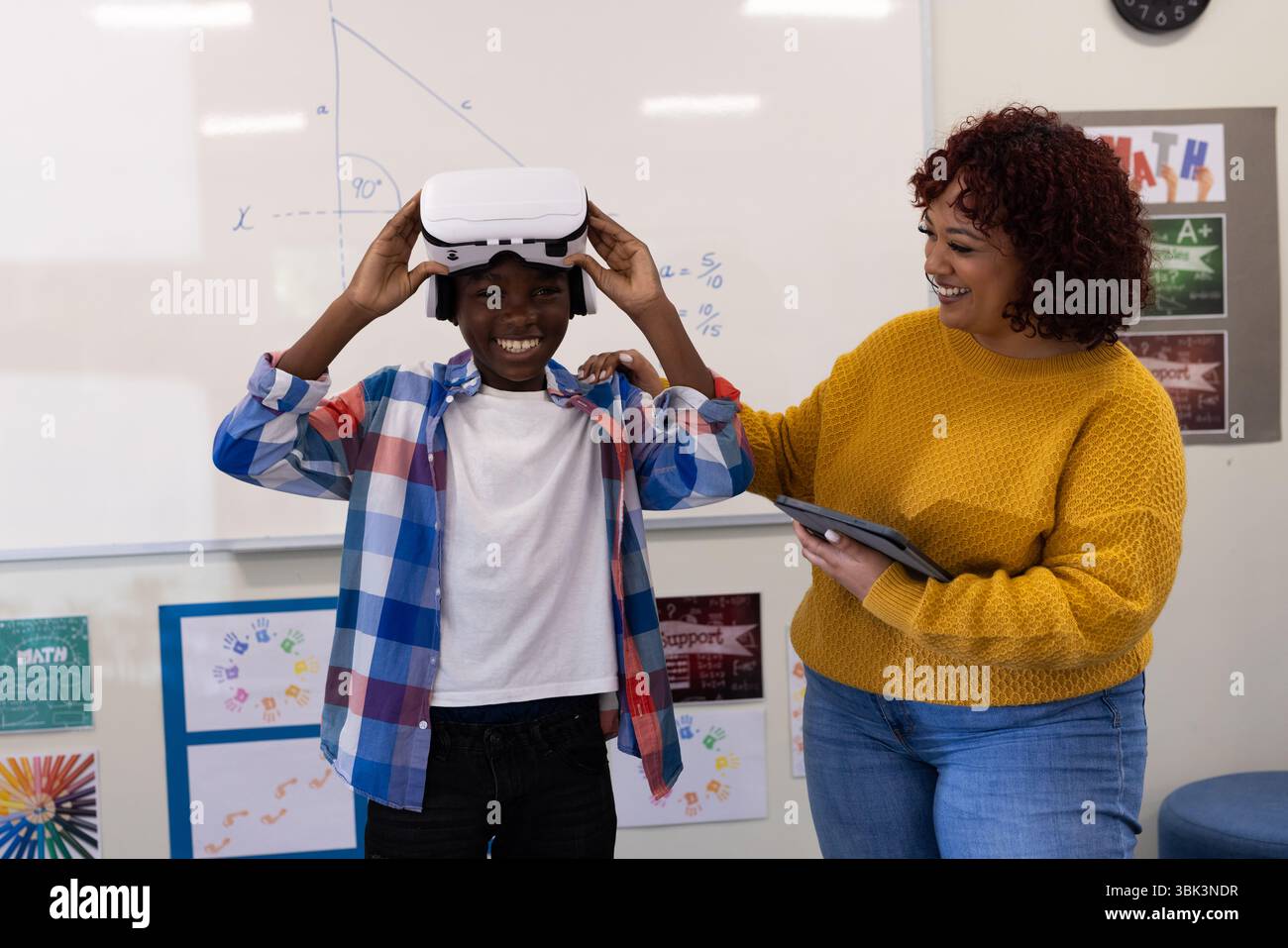 African american boy wearing vr headset in classroom, female teacher ...