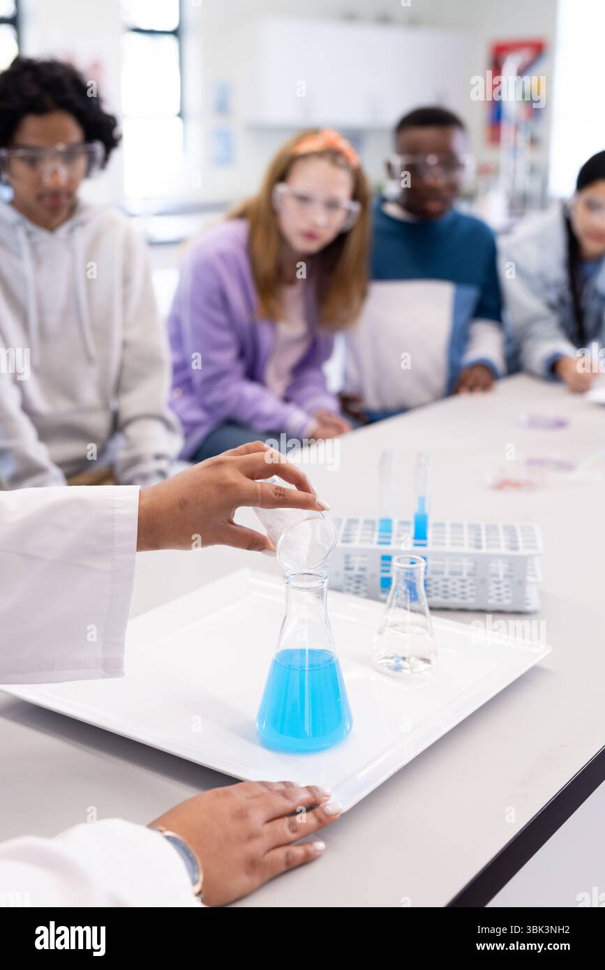 Diverse students observing science experiment with blue liquid in ...