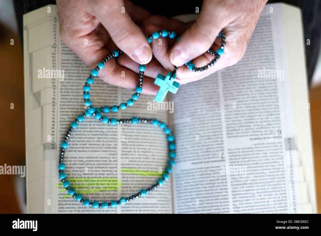 Man praying the rosary and the Bible at home Stock Photo - Alamy
