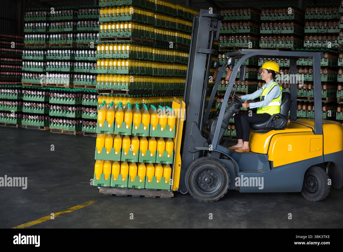 Forklift operator wearing helmet, hi-vis vest is lifting pallet of ...