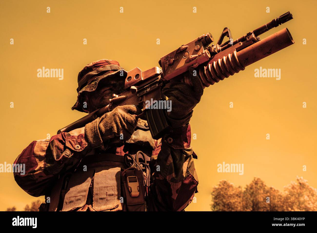 Soldier in camouflage attire and field helmet aiming a rifle with ...