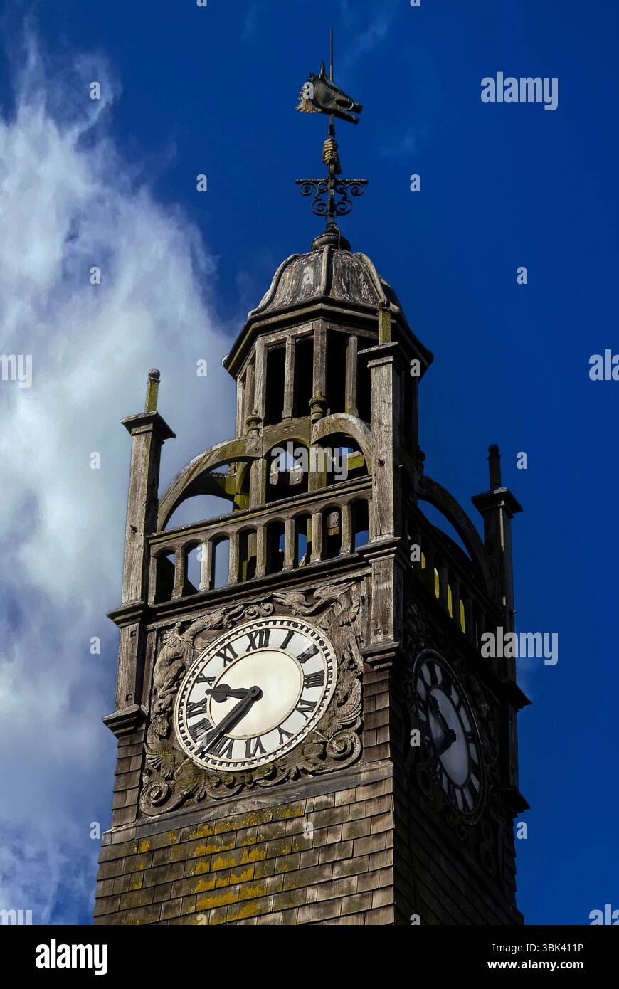 Mythical winged beasts, carved in oak, flank white clock face below ...