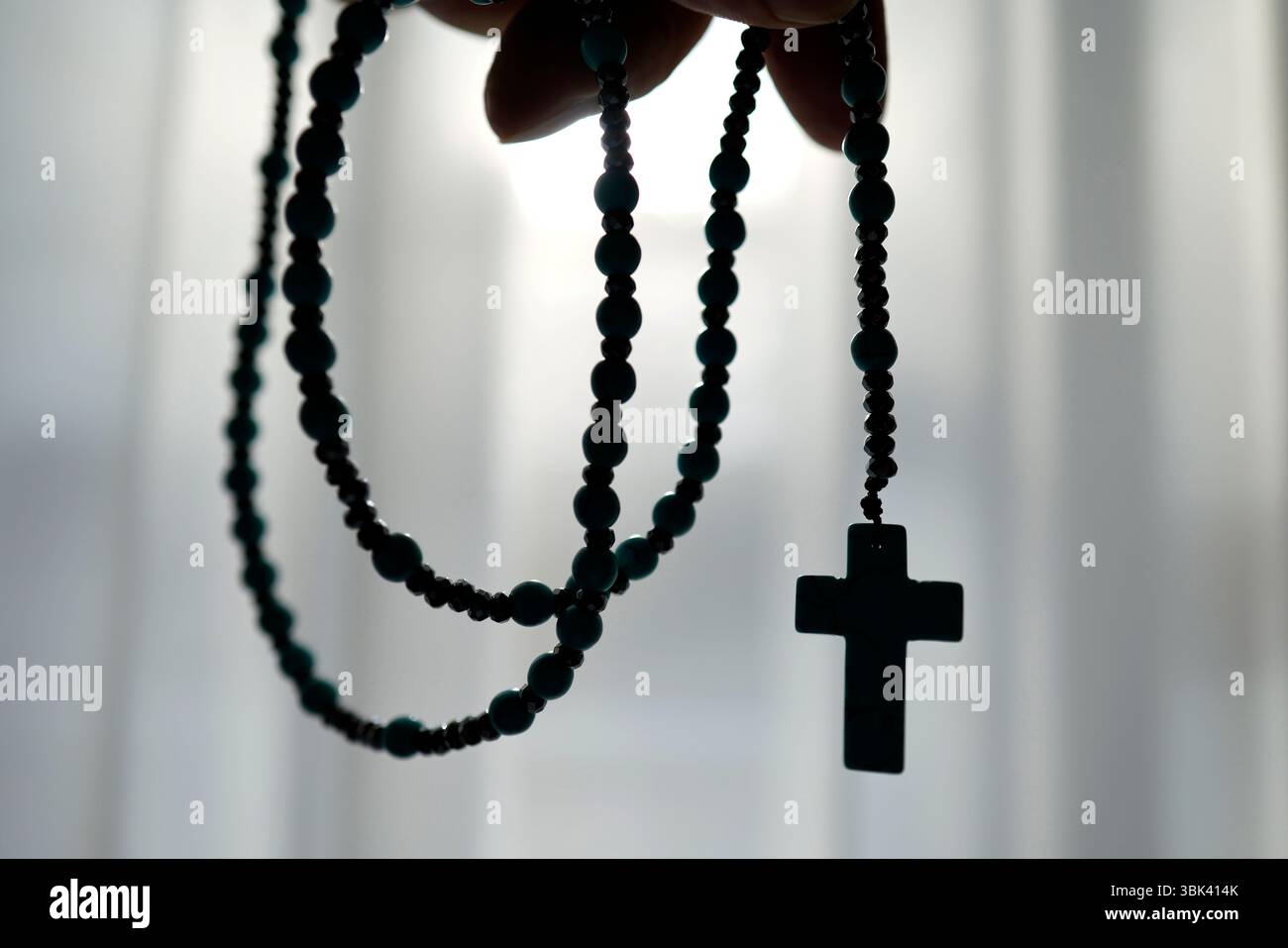 Silhouette of a man's hand praying the rosary Stock Photo - Alamy