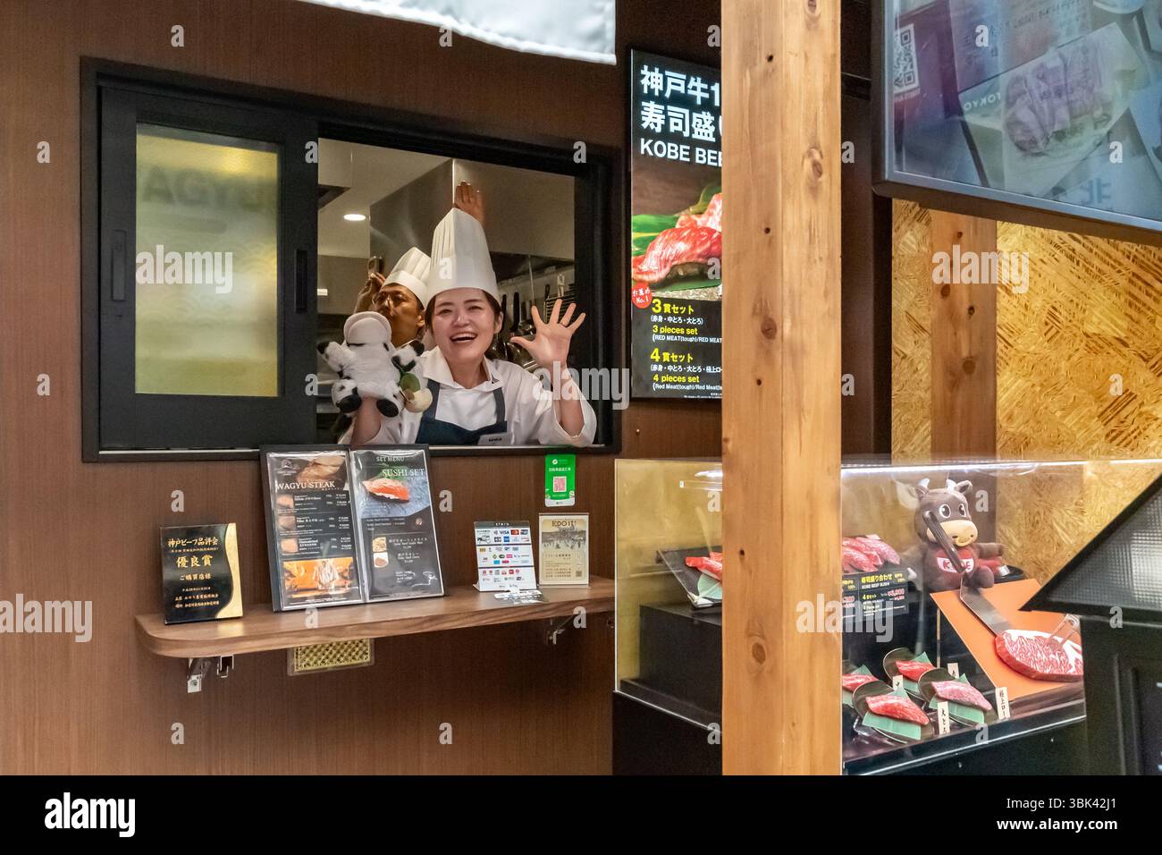 Girl working in take away food restaurant waving with glove puppet in ...