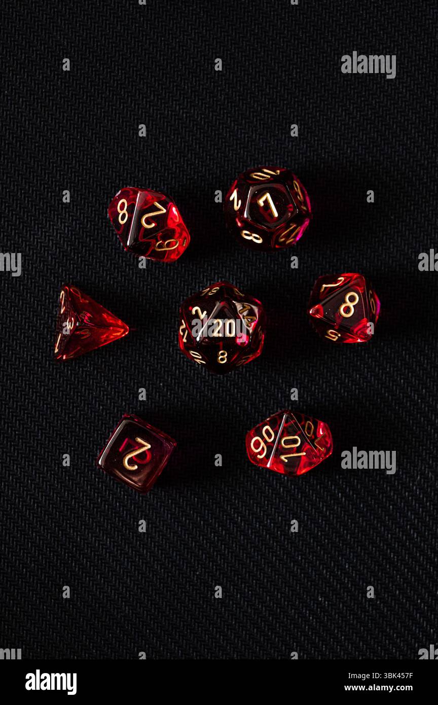 A complete seven-piece set of translucent red polyhedral dice, neatly ...