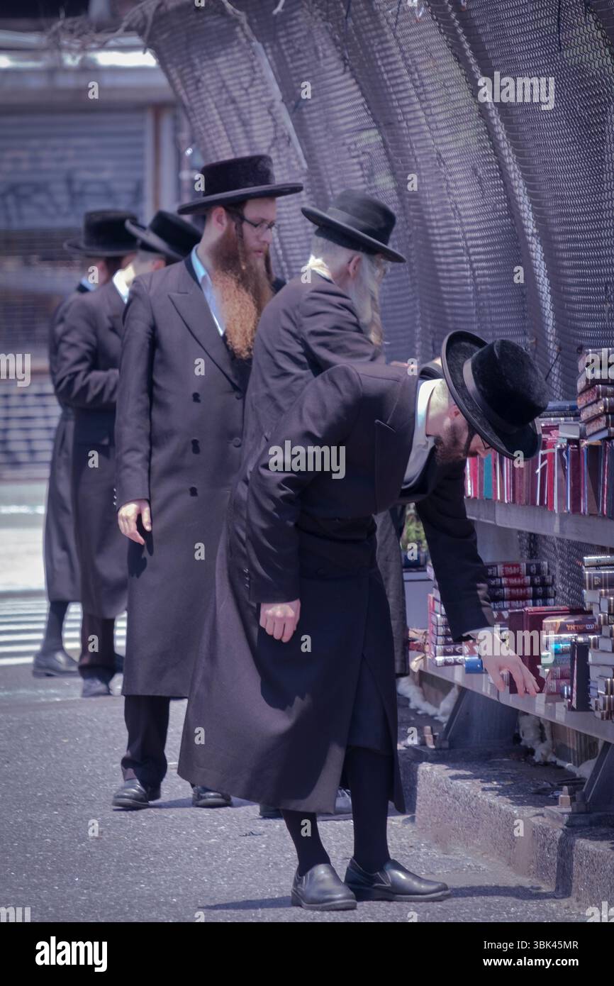 A group of orthodox Jewish men browse the religious books for sale at a ...
