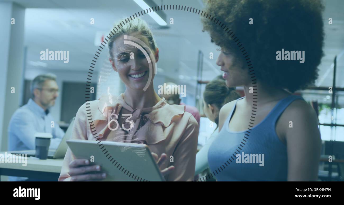 Two women wearing business attire examining tablet screen in modern ...