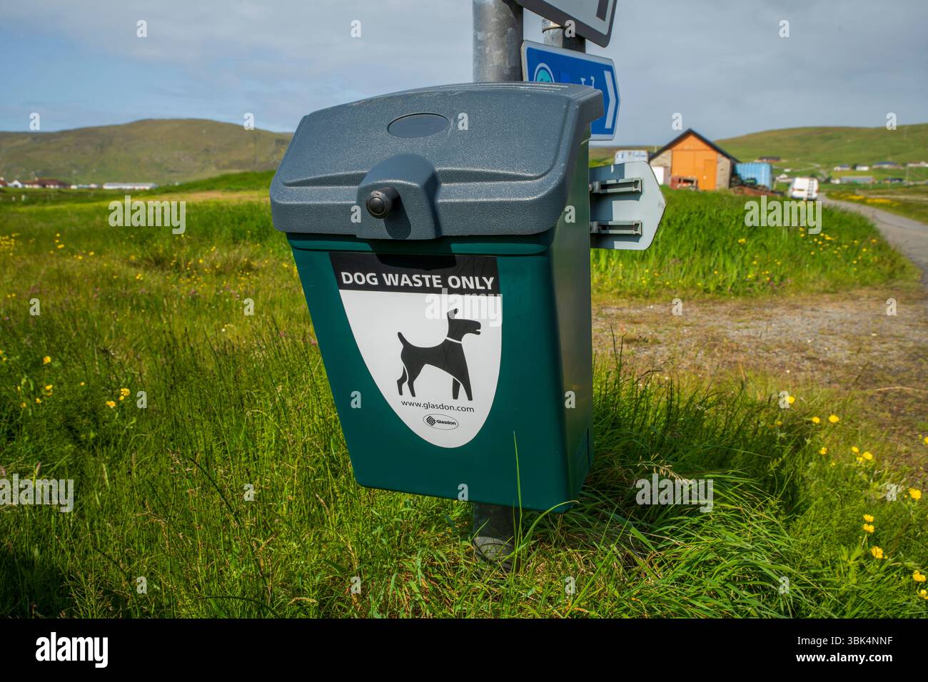 Brightly marked dog waste bin in a rural Shetland setting, encouraging ...