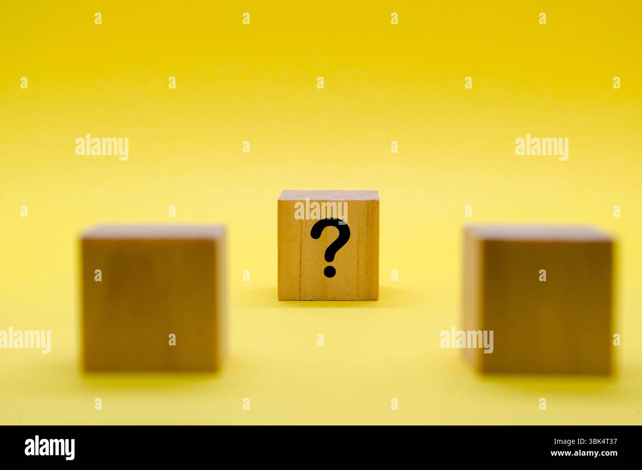 Two wooden cubes with question marks side by side on yellow background ...