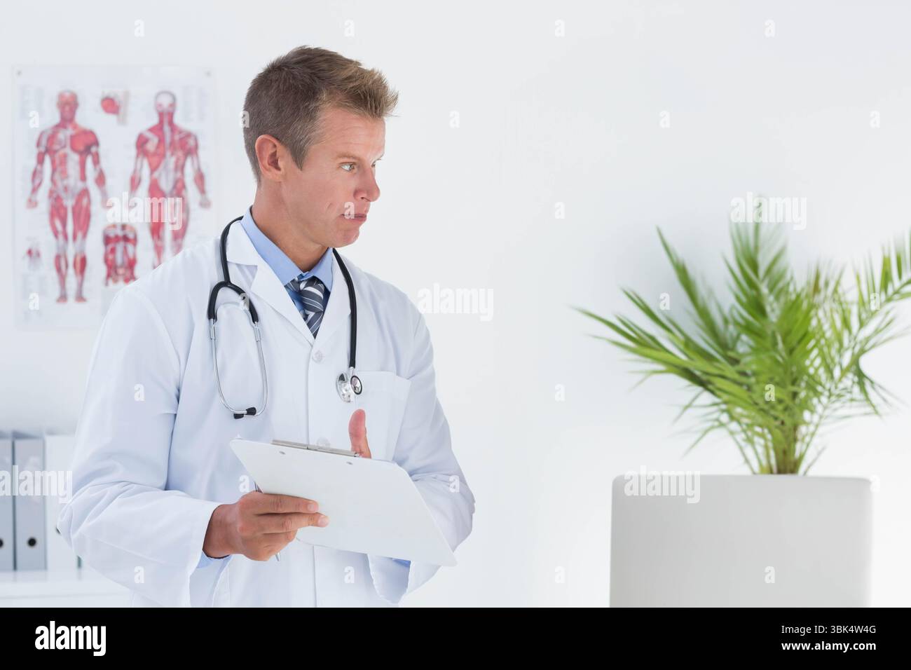 Male doctor wearing lab coat and holding clipboard stethoscope near ...