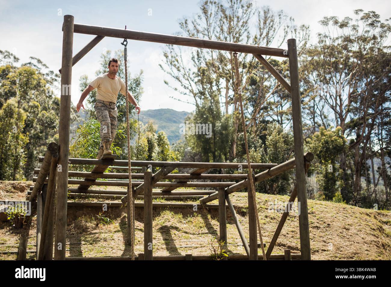 Fit male balancing on wooden platform on outdoor obstacle course with ...