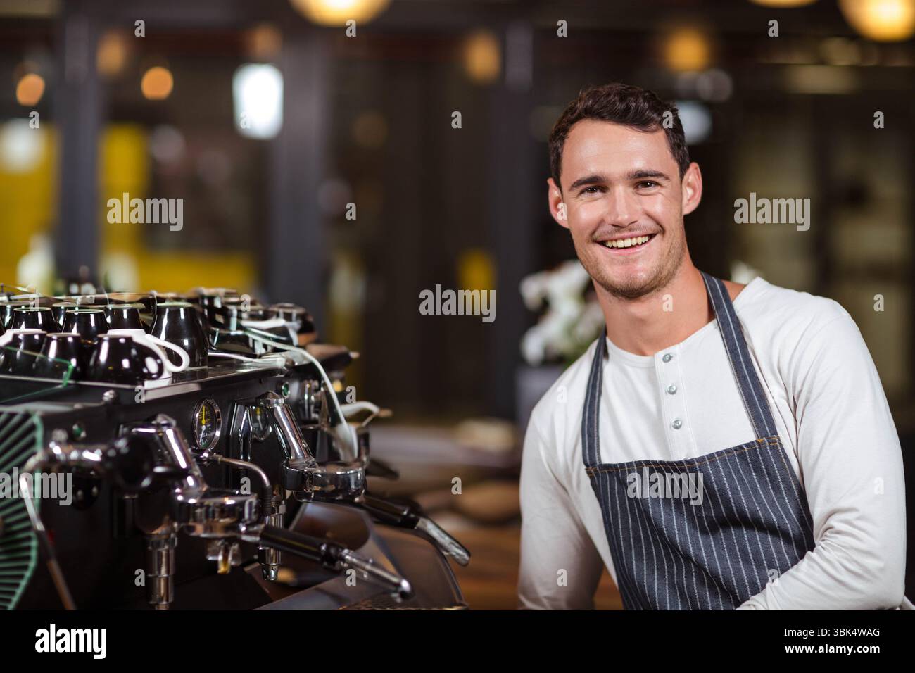 Barista standing behind espresso machine with stacked coffee cups ...