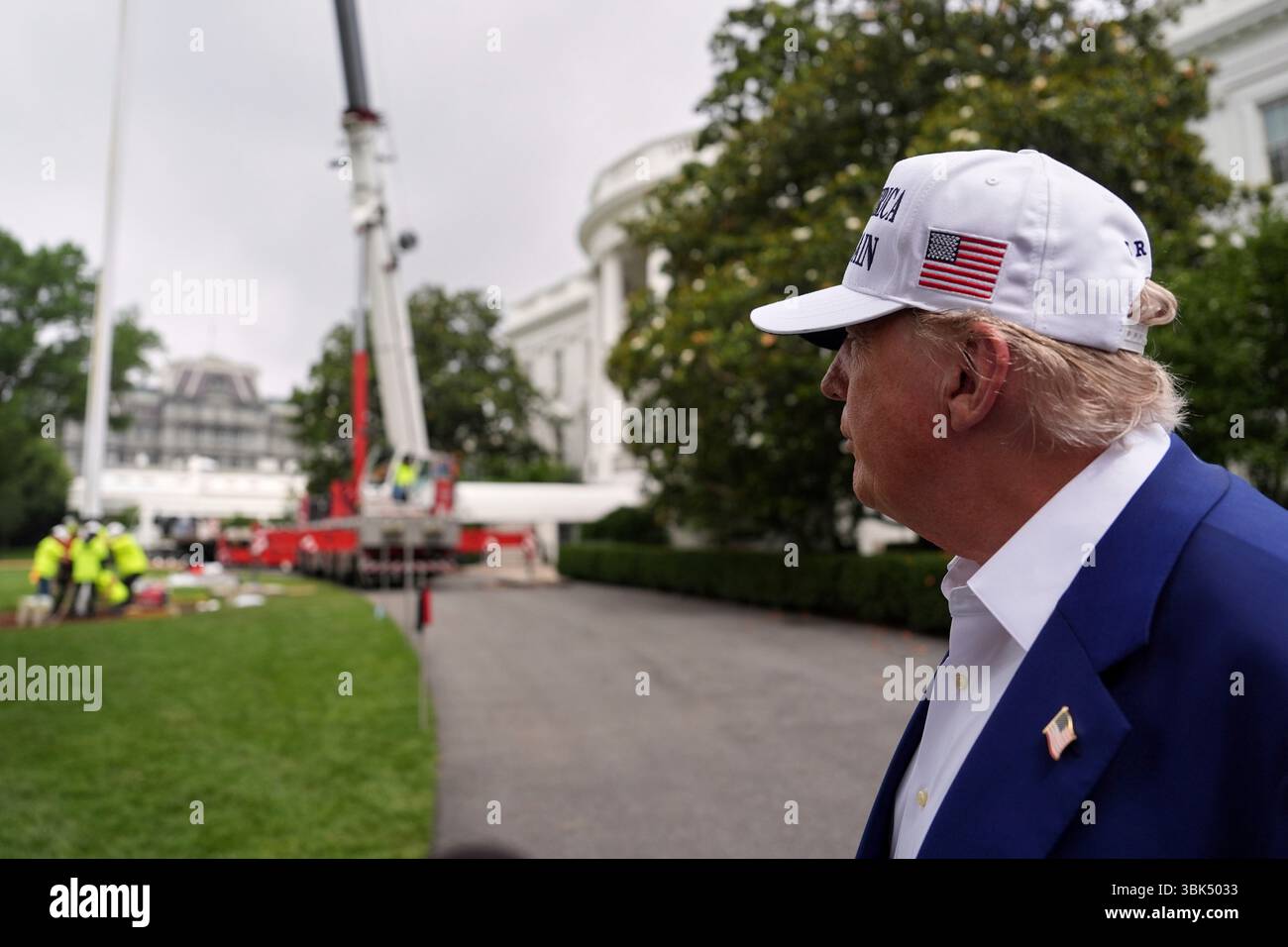President Donald Trump looks on as a flag pole is installed on the ...