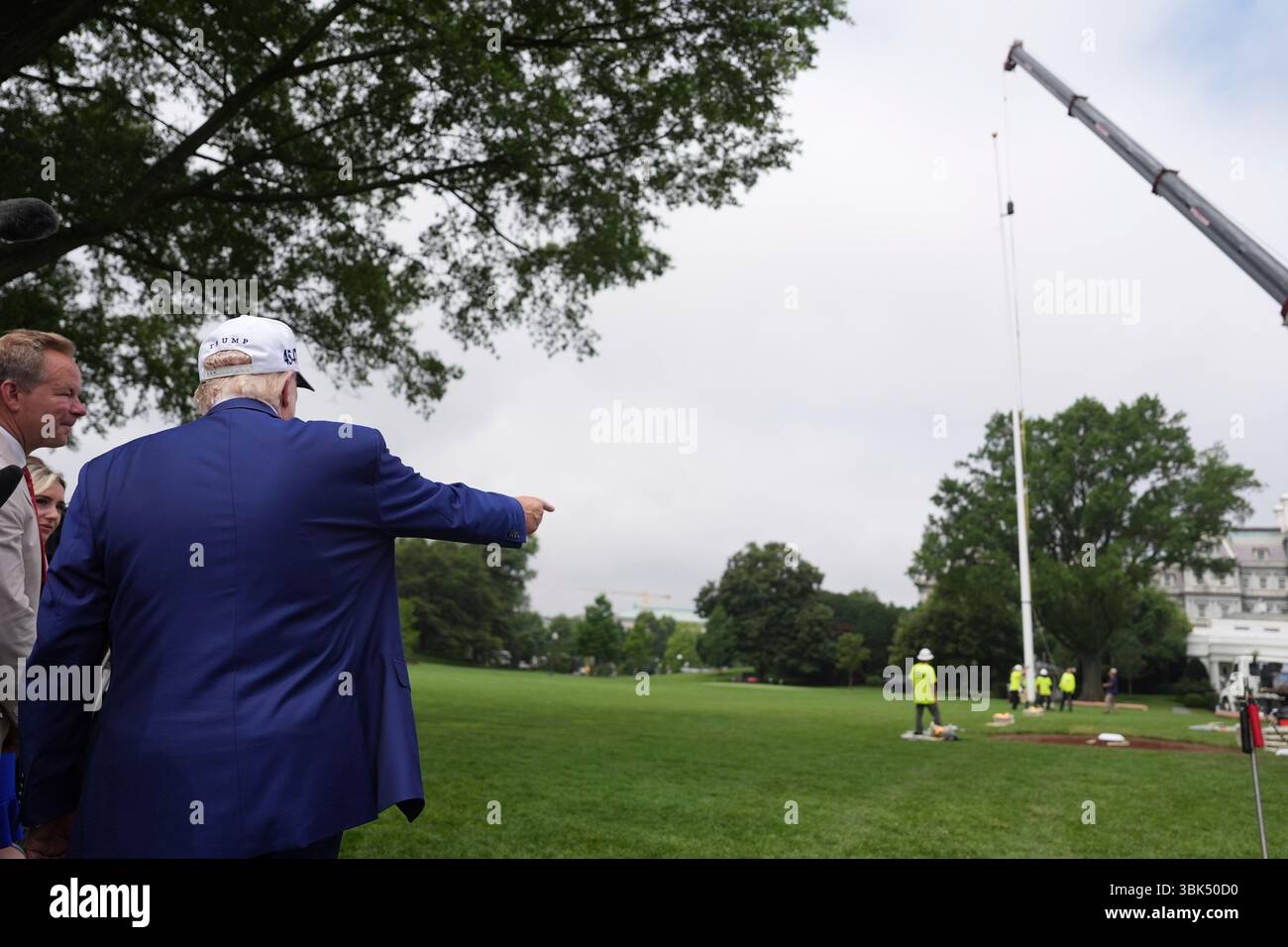 President Donald Trump looks on as a flag pole is installed on the ...