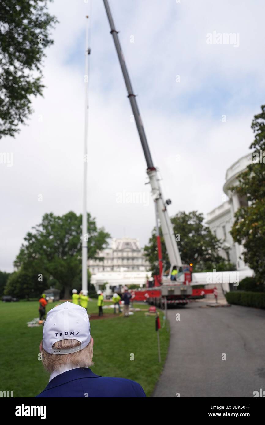 President Donald Trump looks on as a flag pole is installed on the ...