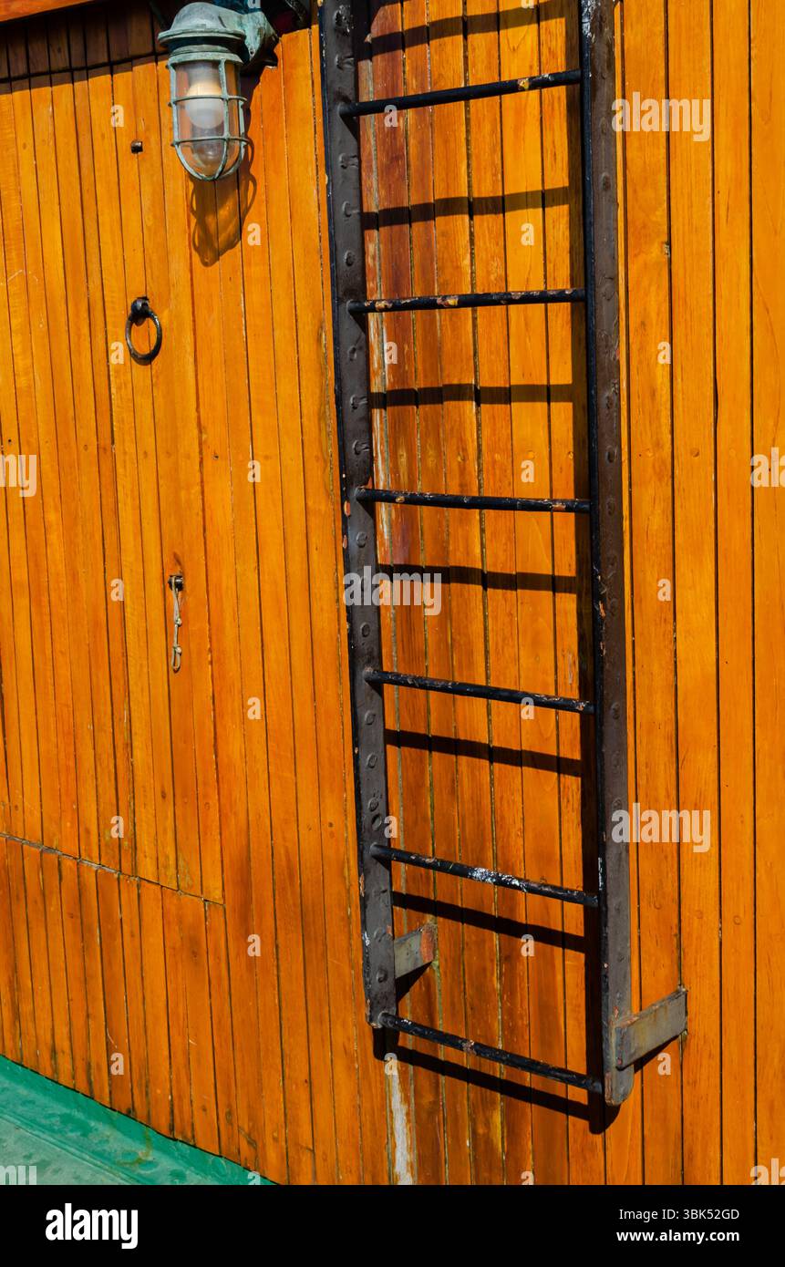 Close-up of Tall Ship's iron ladder on cabin wooden plank wall next to ...