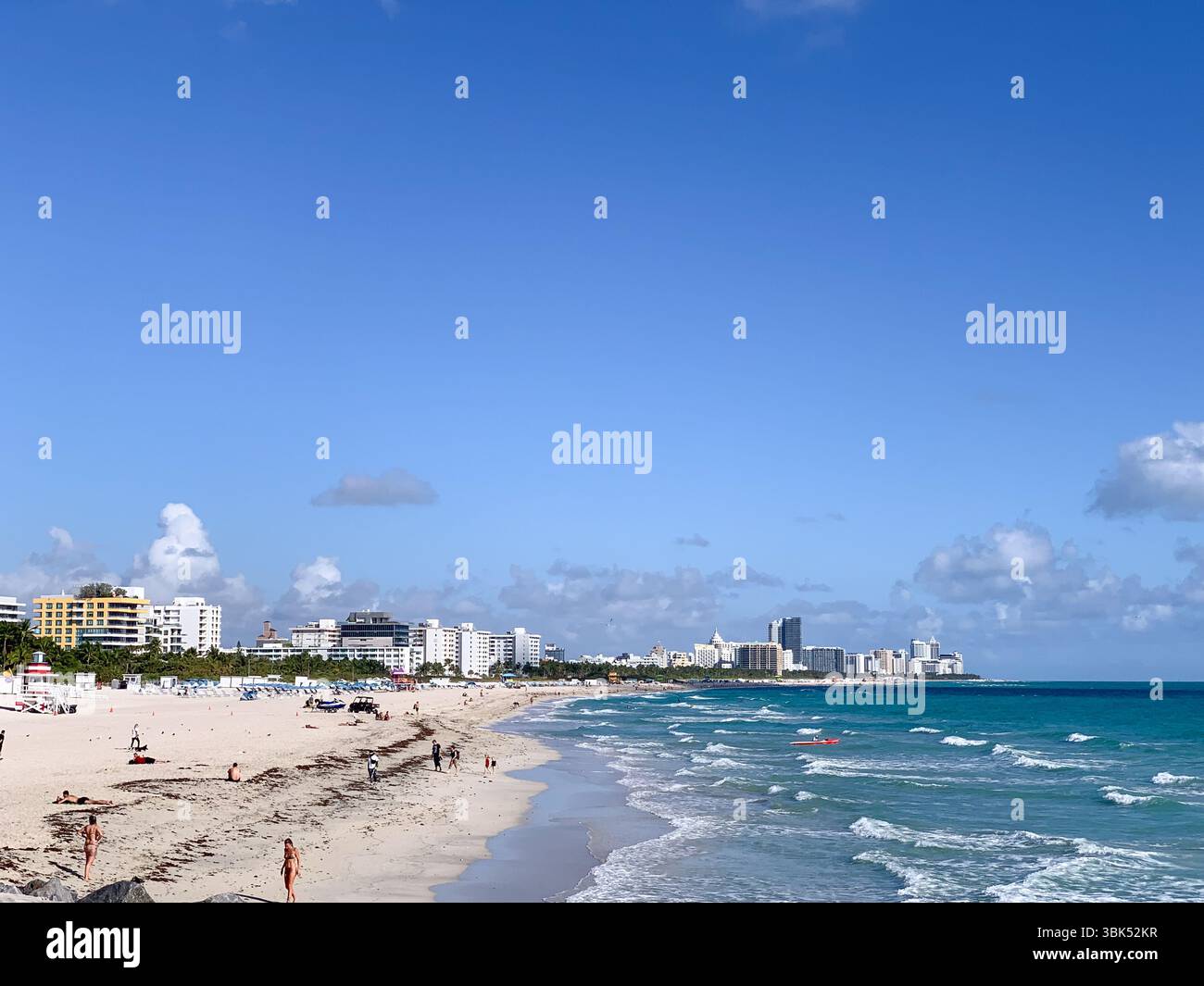 A bright, sunny view of Miami Beach with turquoise ocean waves, white ...