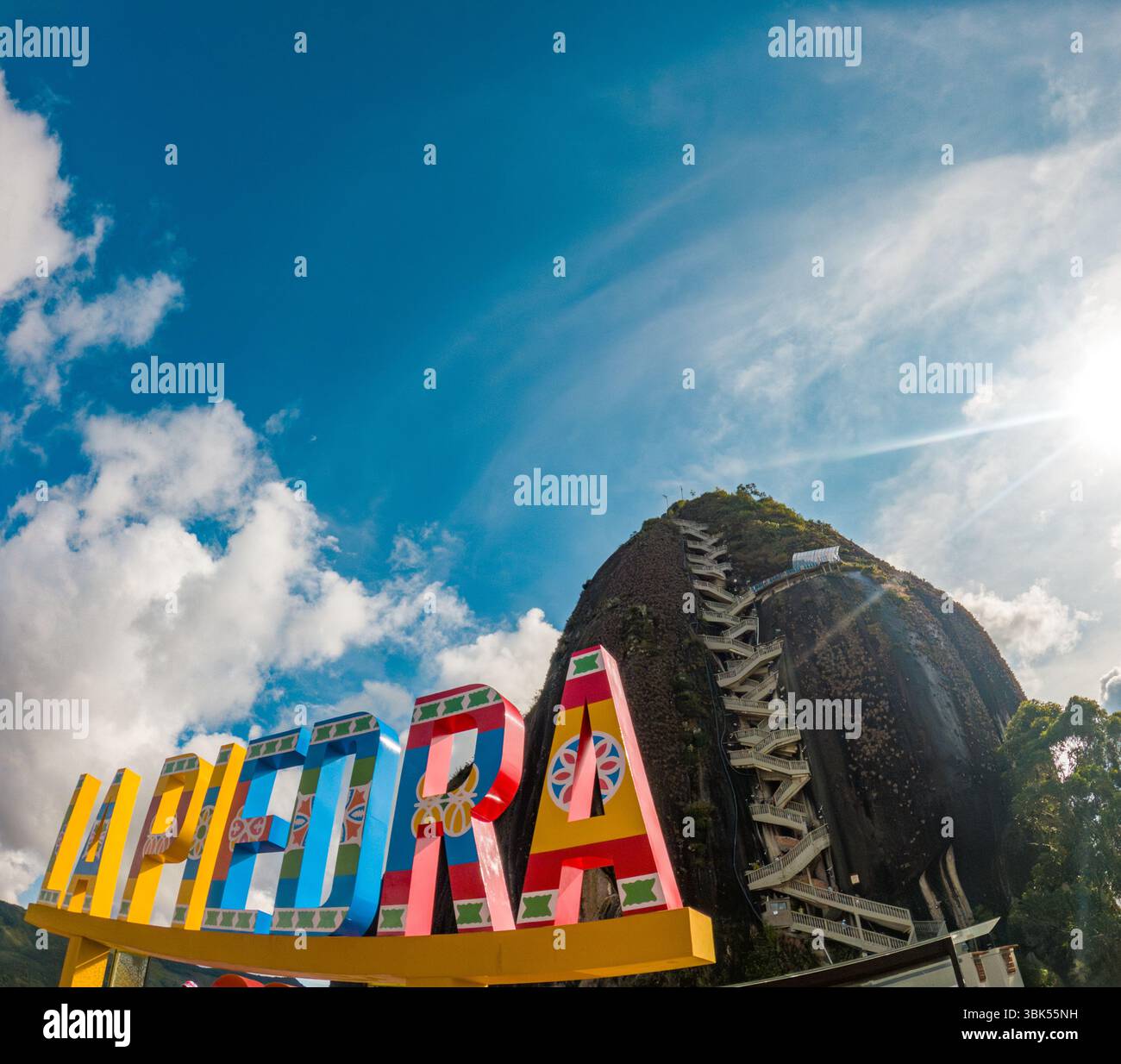 A colorful sign at the base of the iconic Peñol Stone, against a ...